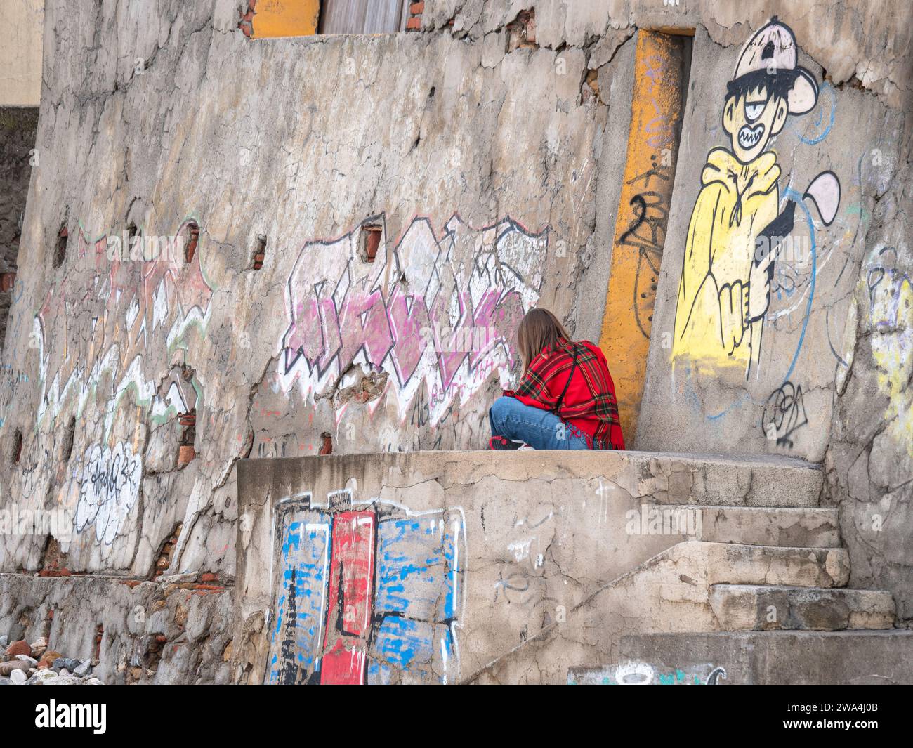 Sad and Lonely Girl Sitting on a Little Wall with Murals by the Sea ...