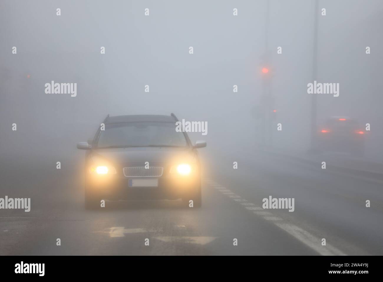 Front view of a black car with bright headlights driving on city street ...