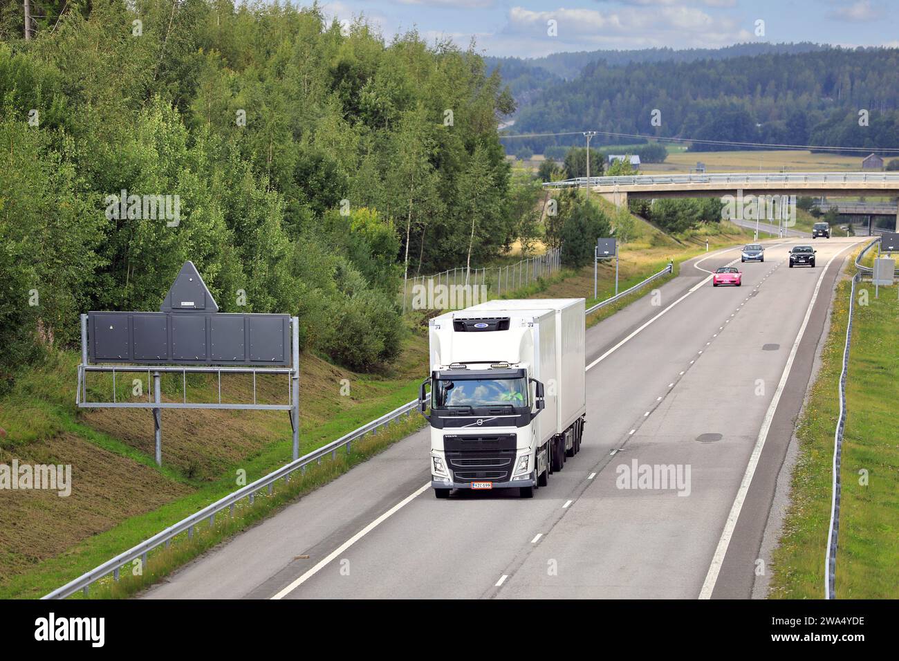 White Volvo FH truck with refrigerated trailer delivers goods on motorway E18 on a day of summer ...