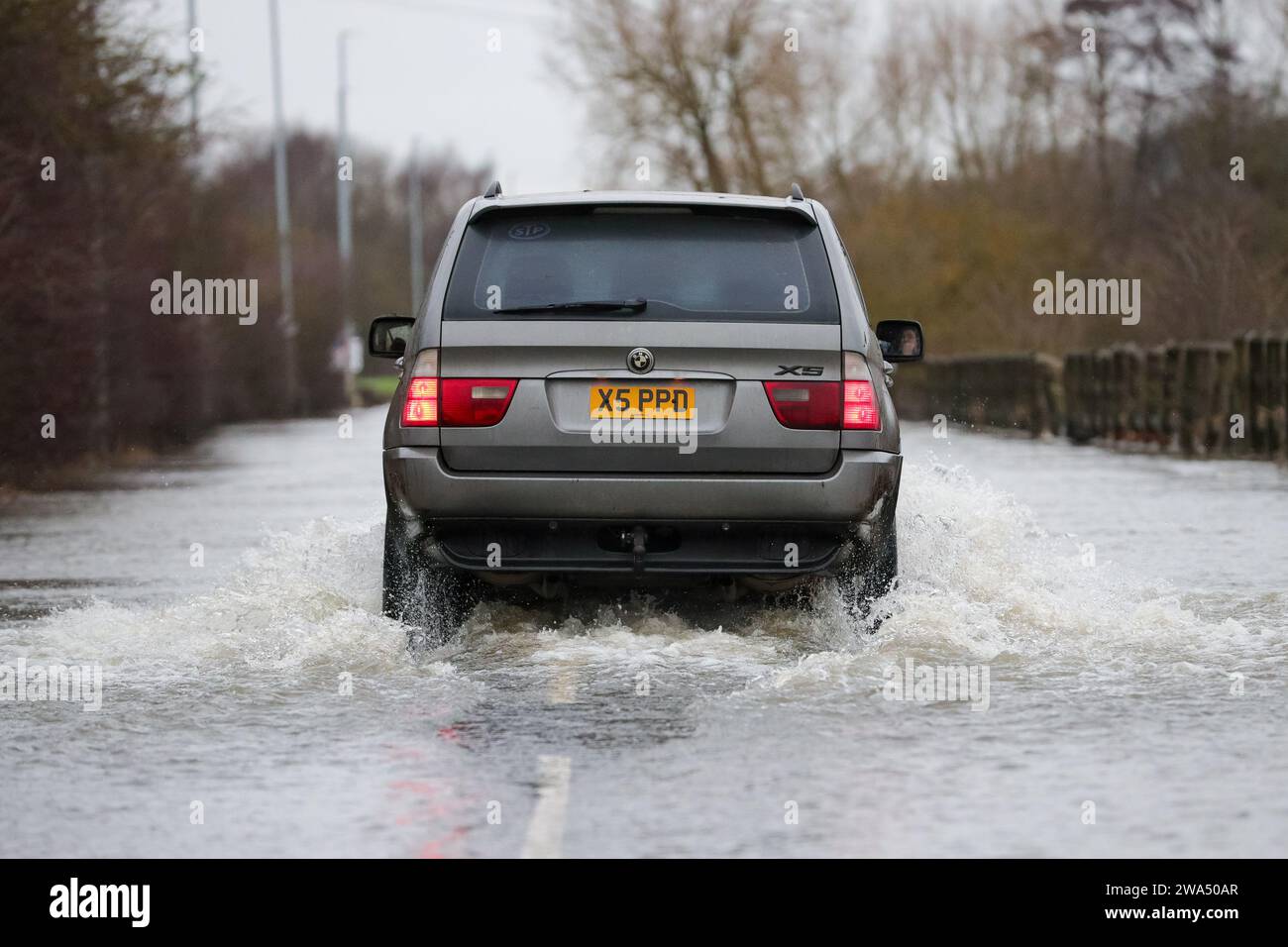 A car makes it’s way through the flooded road caused by storms and ...