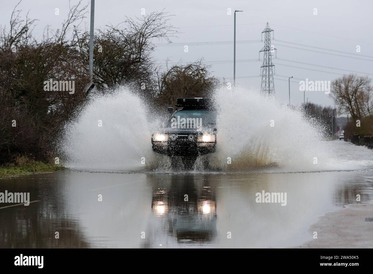 A car makes it’s way through the flooded road caused by storms and ...