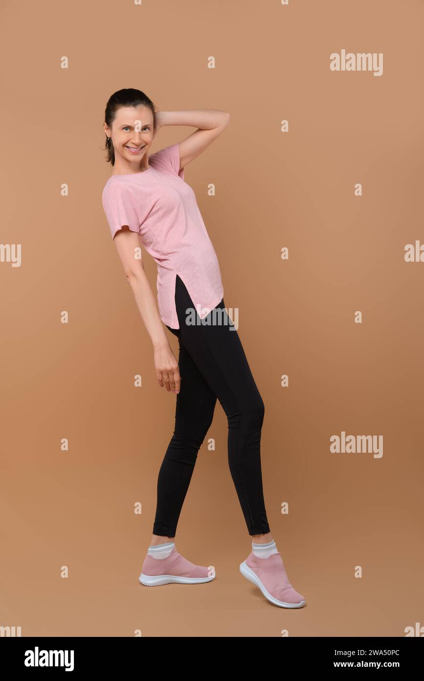 A sportive woman bends backward in a studio, looking at the camera ...