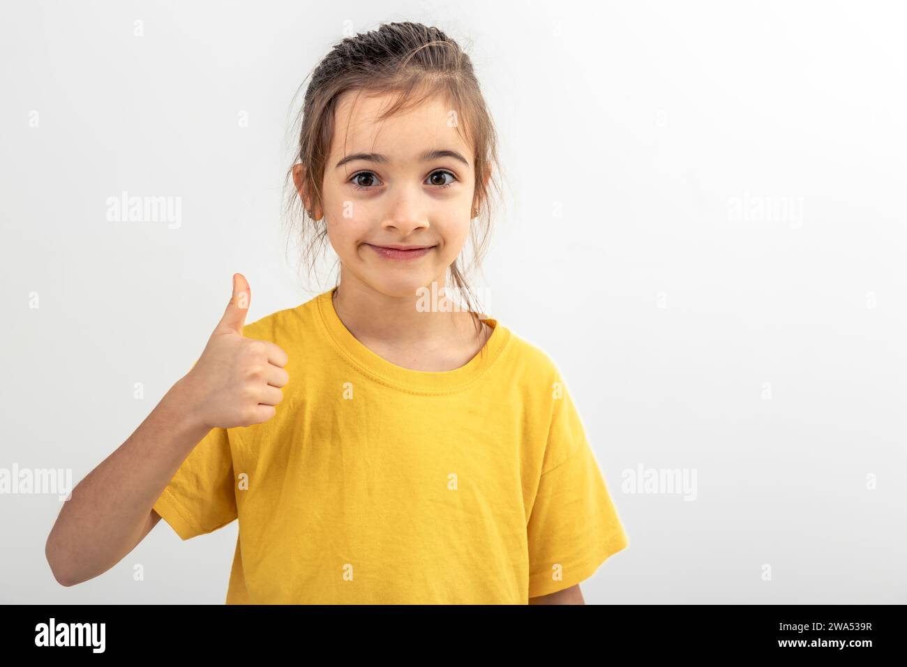 Cheerful little girl showing finger thumb up isolated on white ...