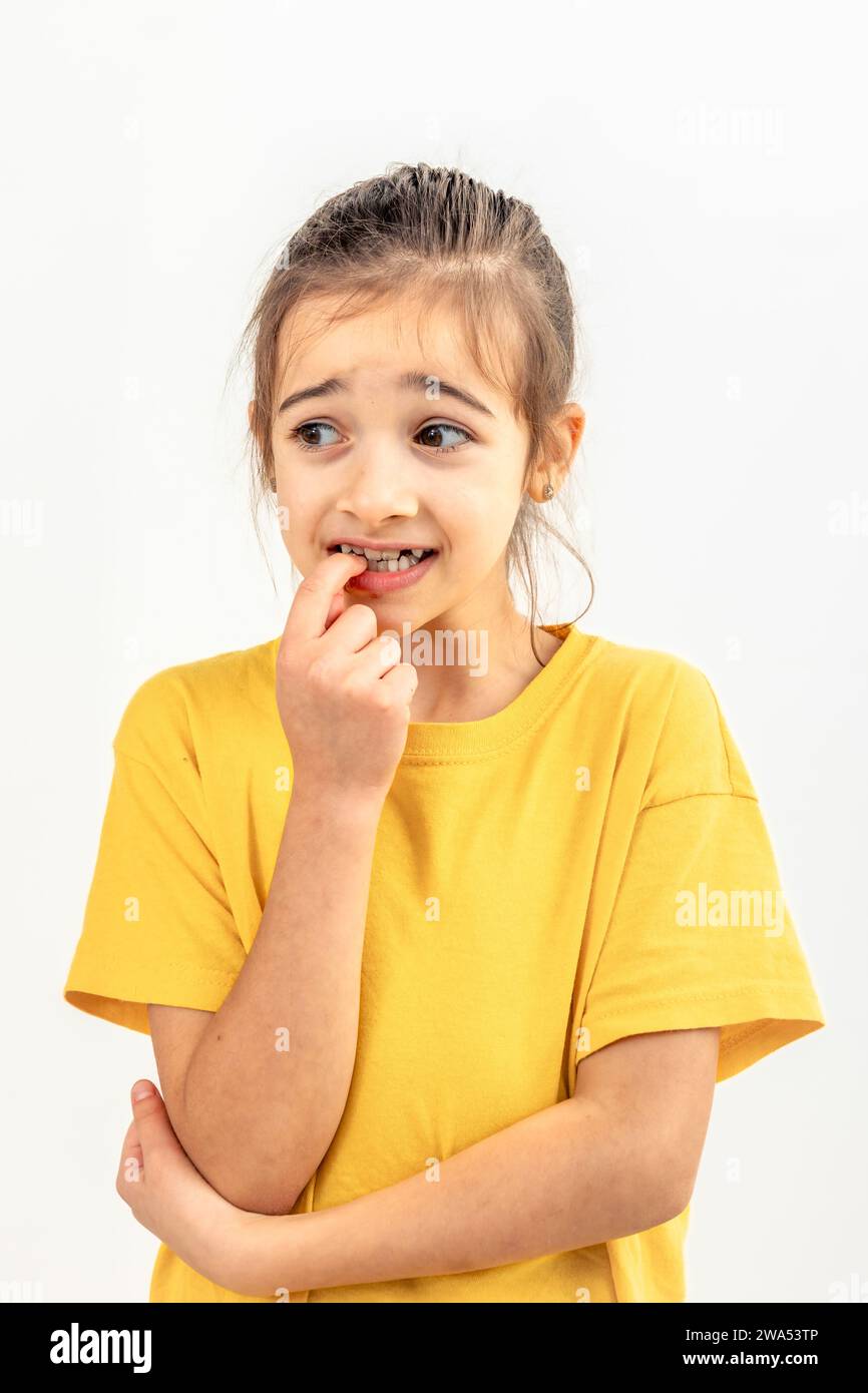 Scared and anxious girl, biting her fingernails on a white background ...