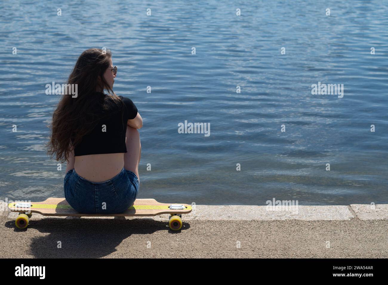 A cool young woman sitting on a longboard Stock Photo - Alamy