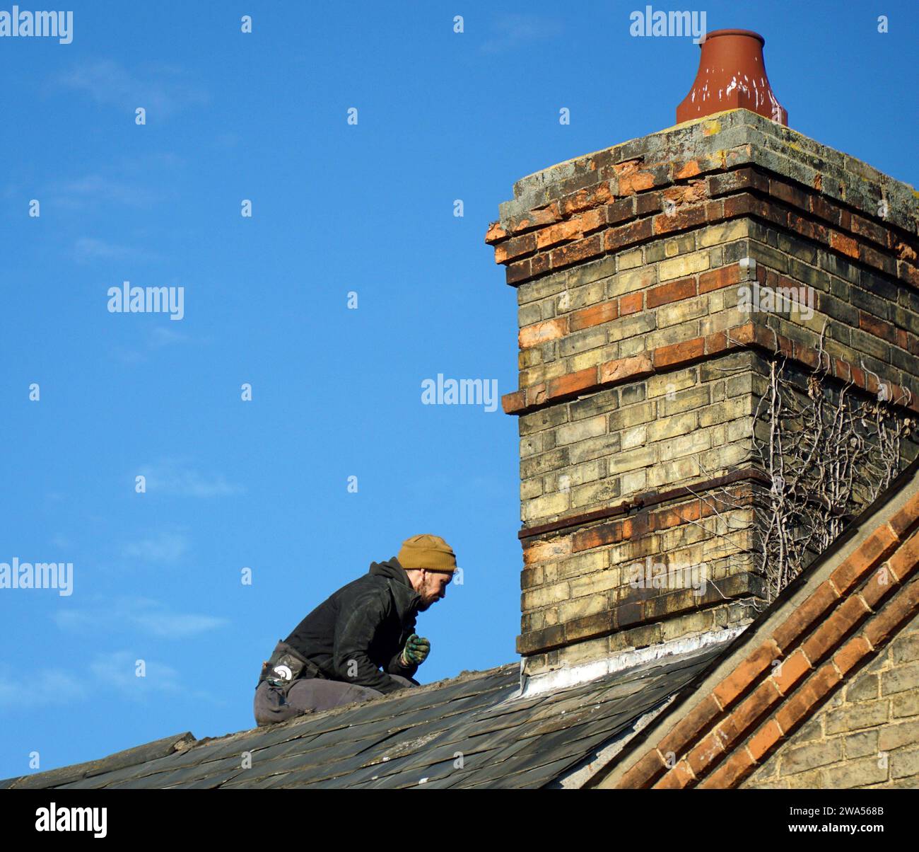 Workman on house roof doing repairs and Victorian Chimney Stock Photo ...