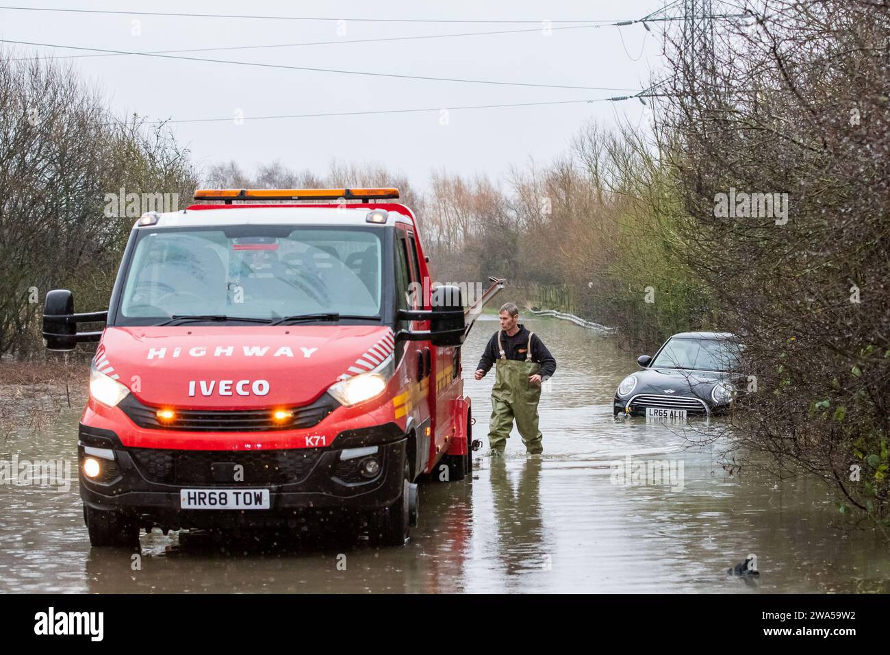 A highway recovery van pulls a car stuck on the flooded road caused by ...