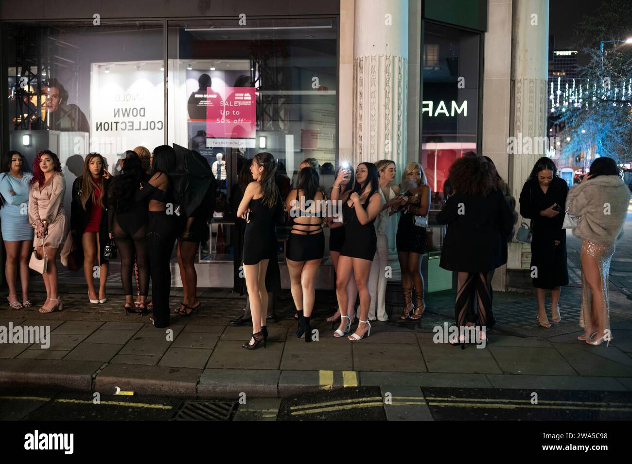 Young women queue up outside a night club on a clod wet New Years Evening in the capital's West ...