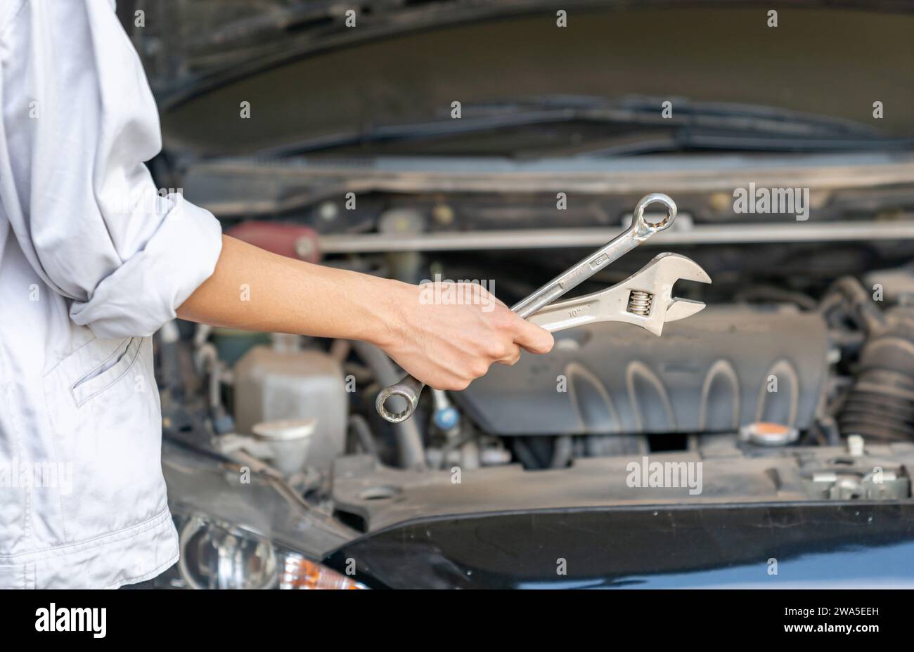 Close up arms holding wrench on car repairing shop. Repair and fixed ...
