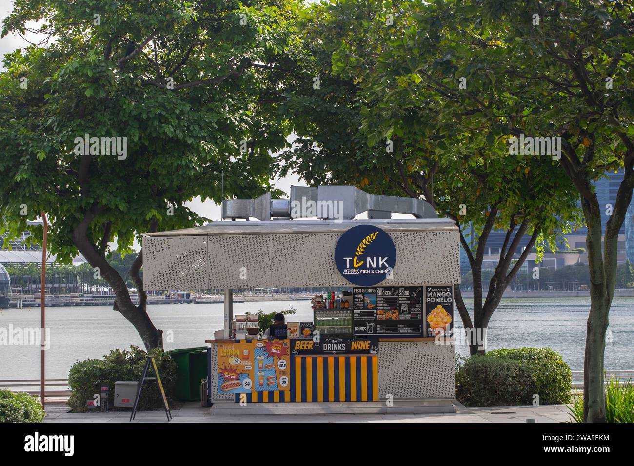 An outdoor kiosk under the tree that sells fish and chips, behind is ...