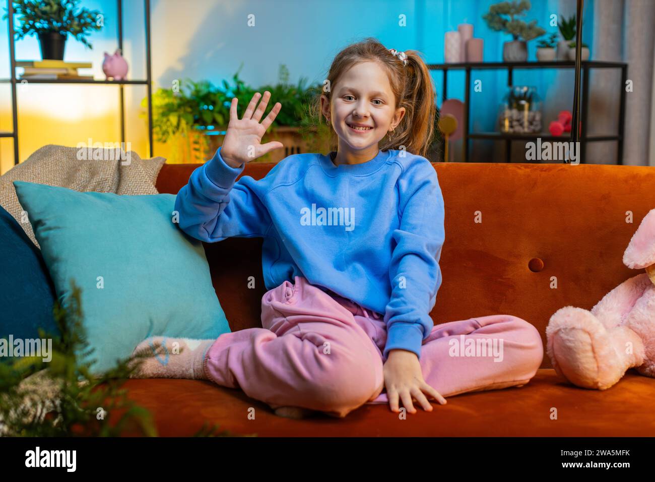 Young child girl smiling friendly at camera and waving hands gesturing ...