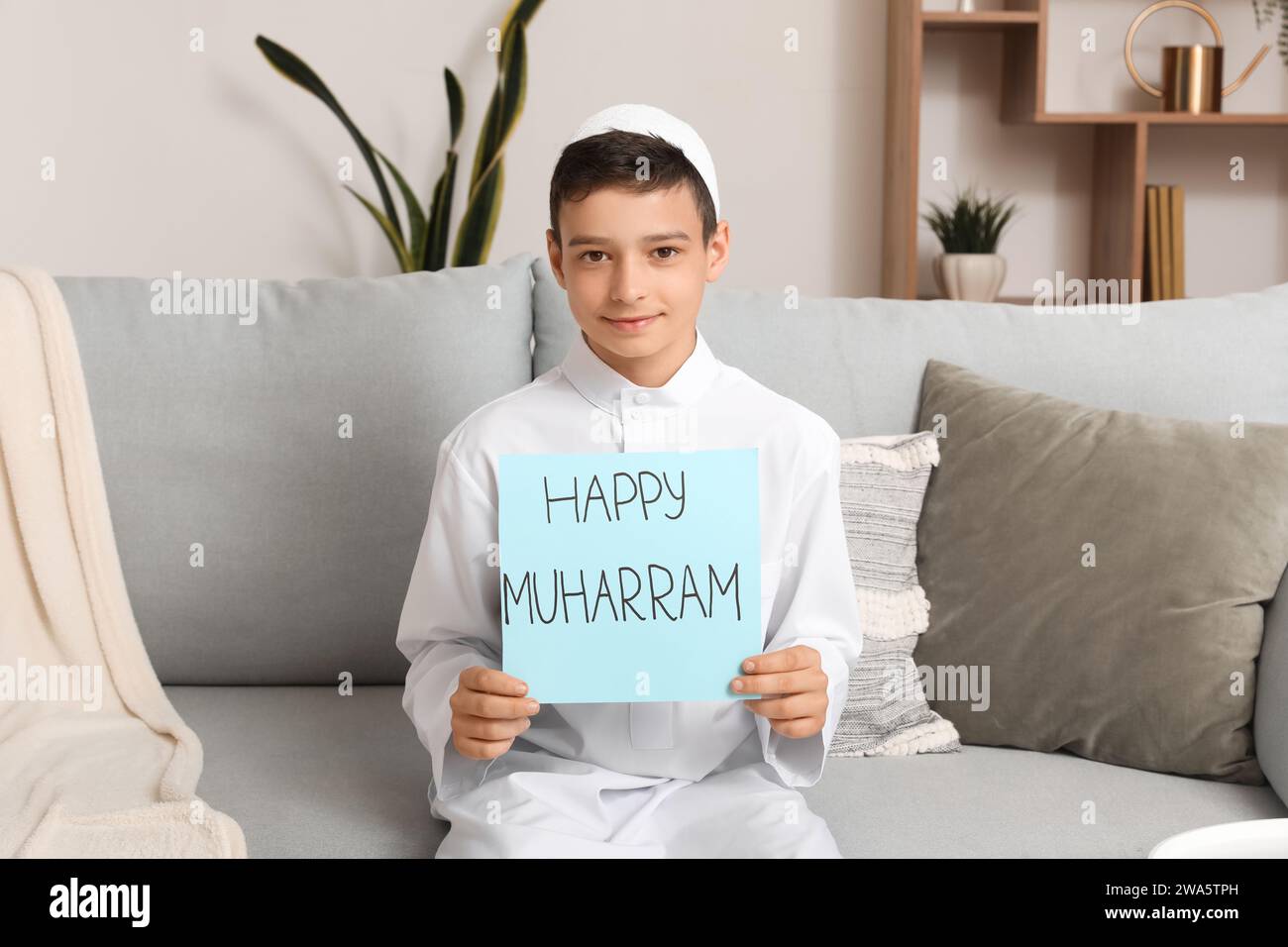 Little Muslim boy with greeting card for Islamic New Year at home Stock ...