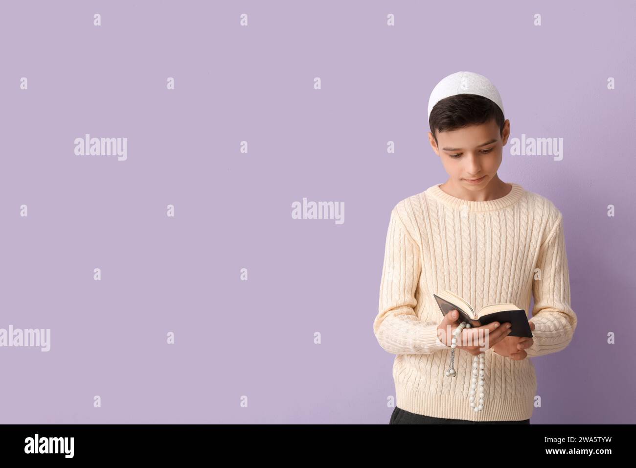 Little Muslim boy with Quran and praying beads on lilac background ...