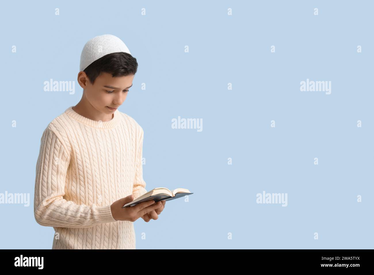 Little Muslim boy with Quran on light blue background Stock Photo - Alamy