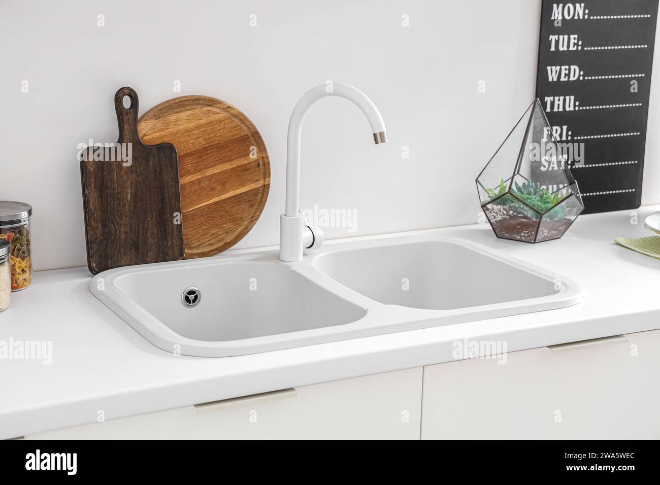 White counters with sink and utensils in interior of modern kitchen ...