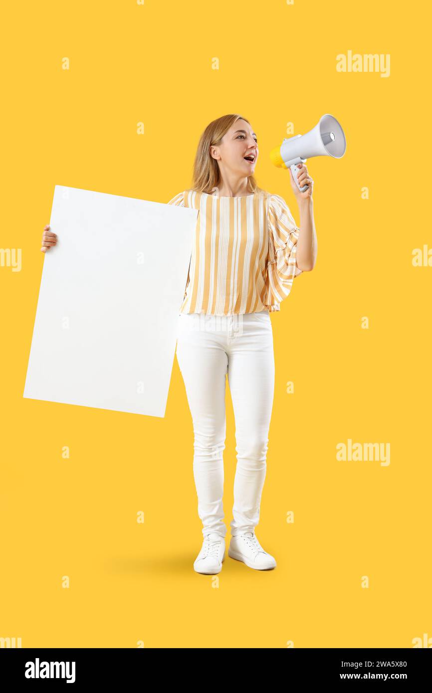 Mature woman with blank poster shouting into megaphone on yellow ...