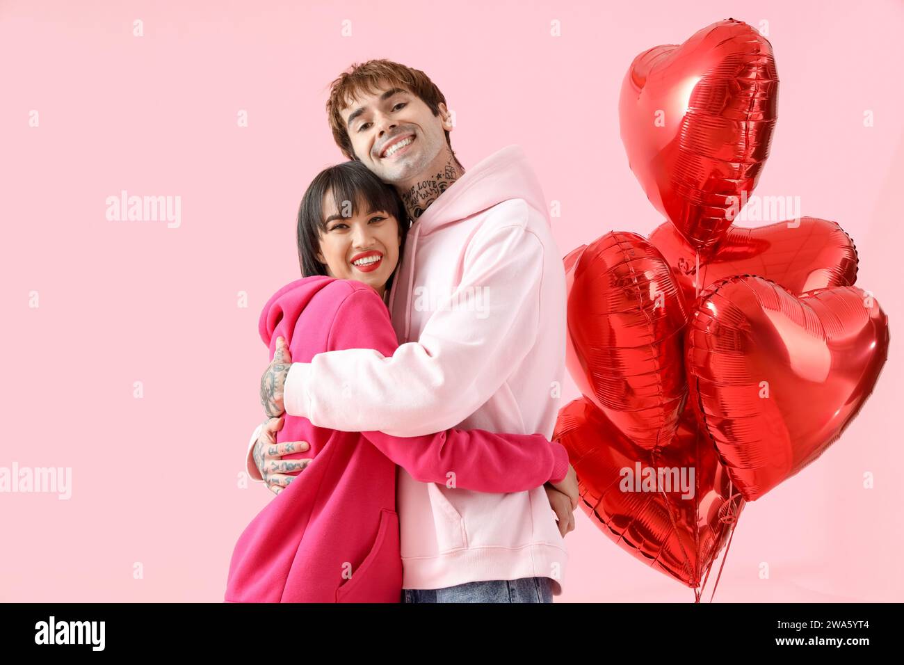 Young couple with balloons hugging on pink background. Valentine's Day ...