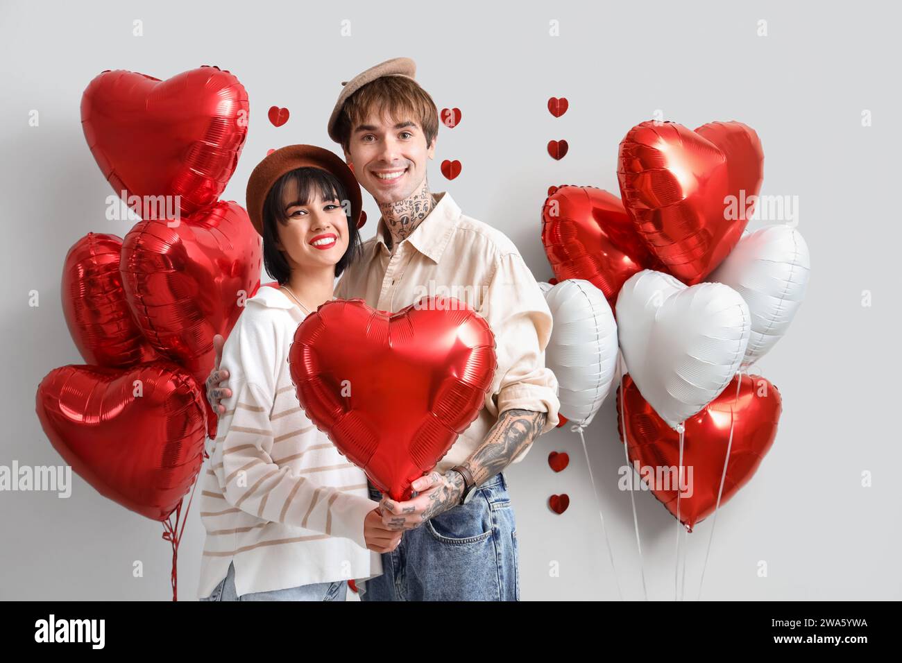 Young couple with balloons hugging on light background. Valentine's Day ...