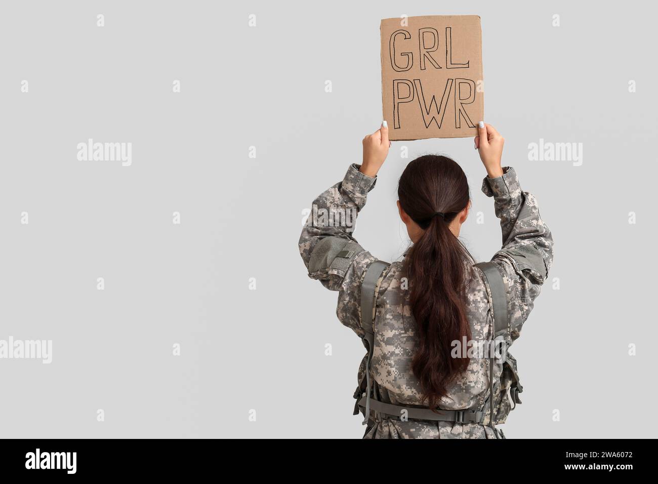Young female soldier with sign GRL PWR on white background, back view ...