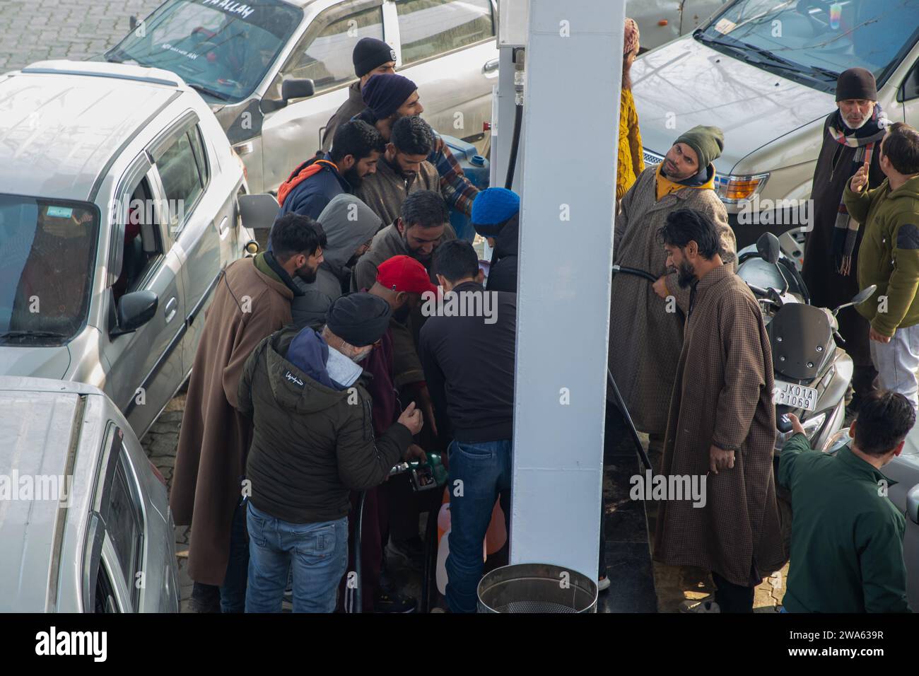 People wait with their vehicles in a queue to refill fuel tanks at a ...