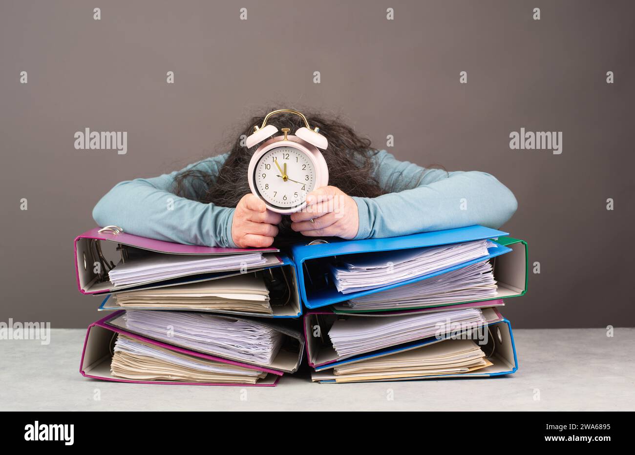 Exhausted tired woman with alarm clock sleeping on a pile of file ...