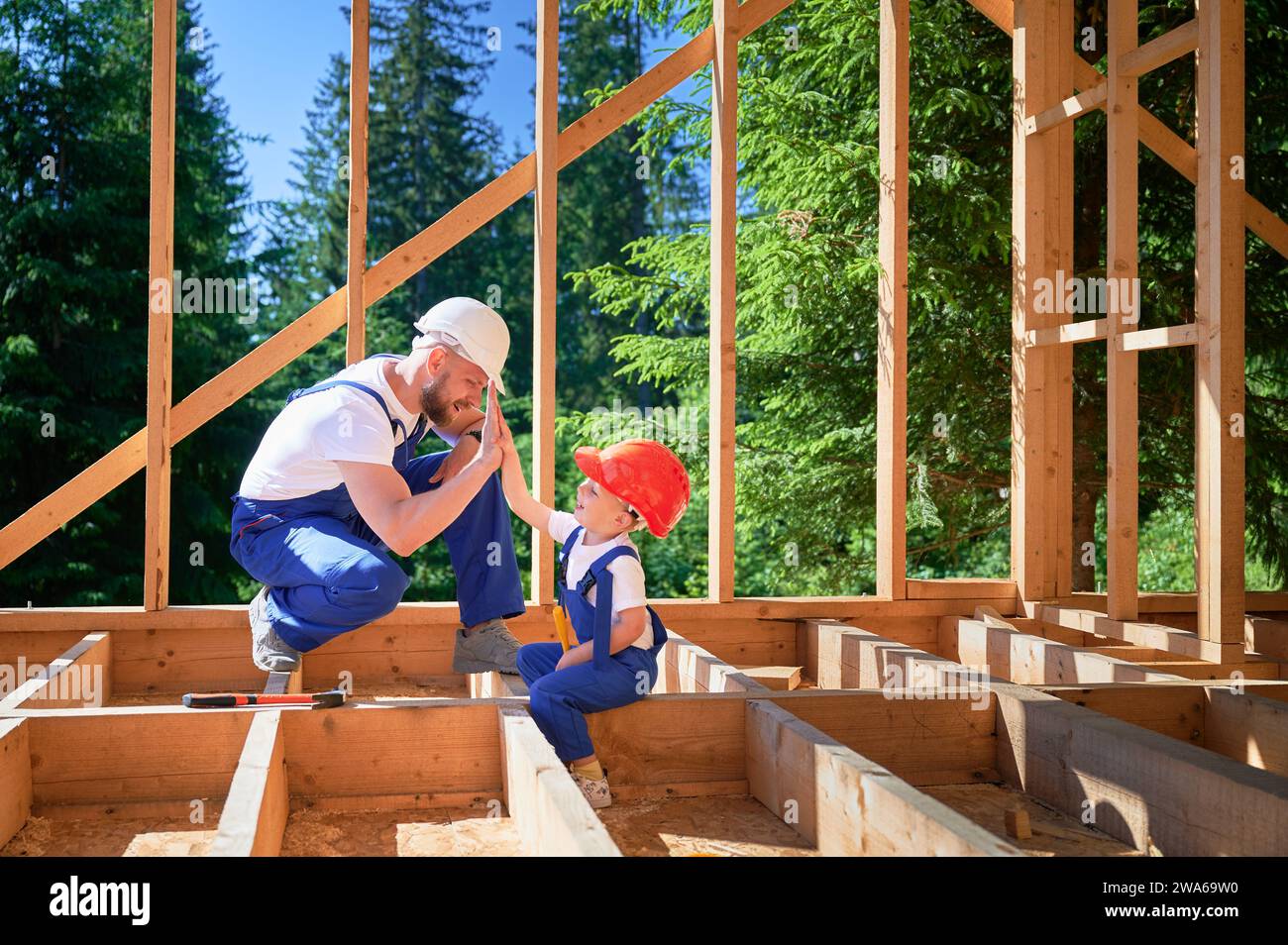 Father with toddler son constructing wooden frame house. Male builder ...