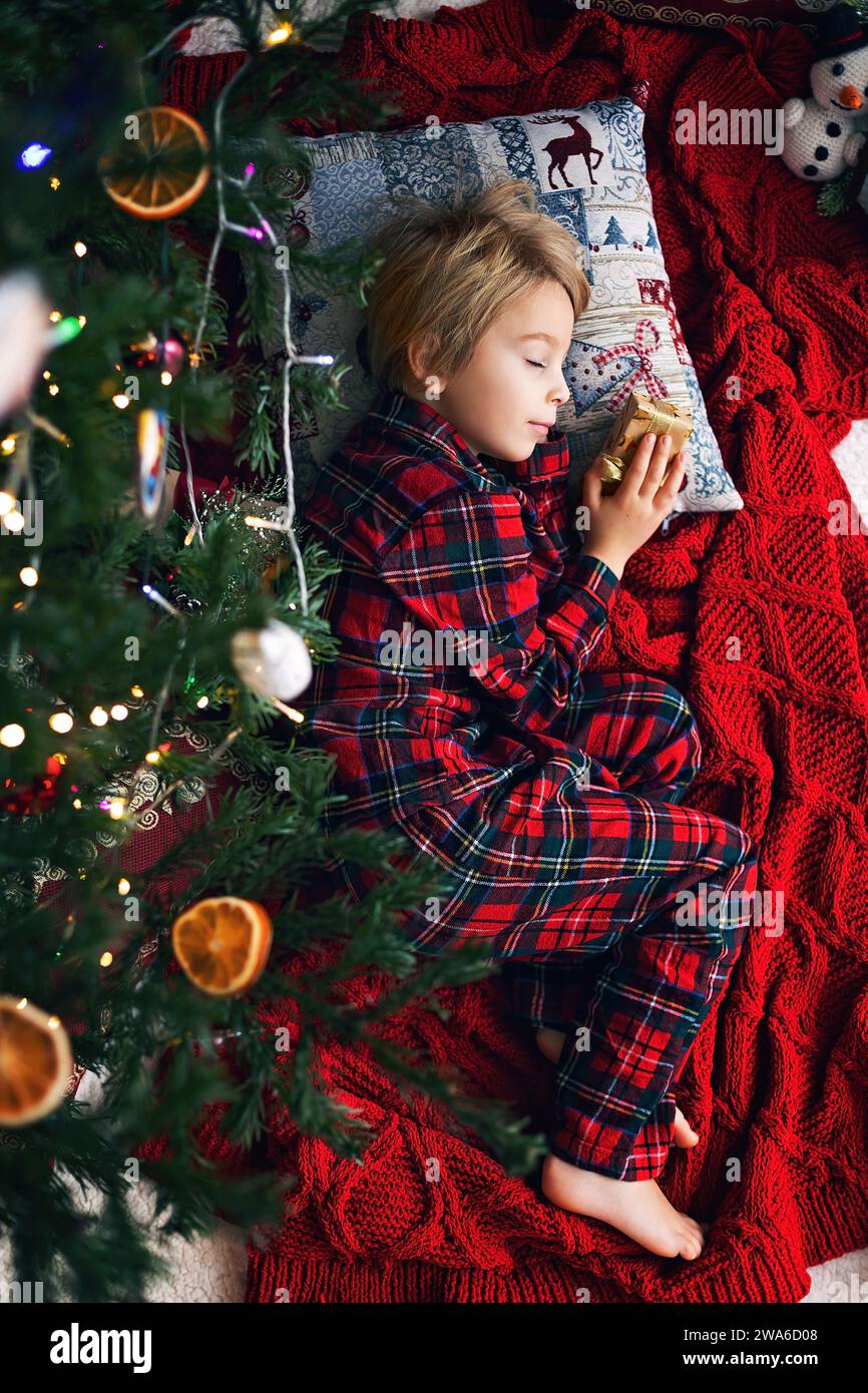 Cute child, cute blond boy, sleeping under the christmas tree, waiting ...