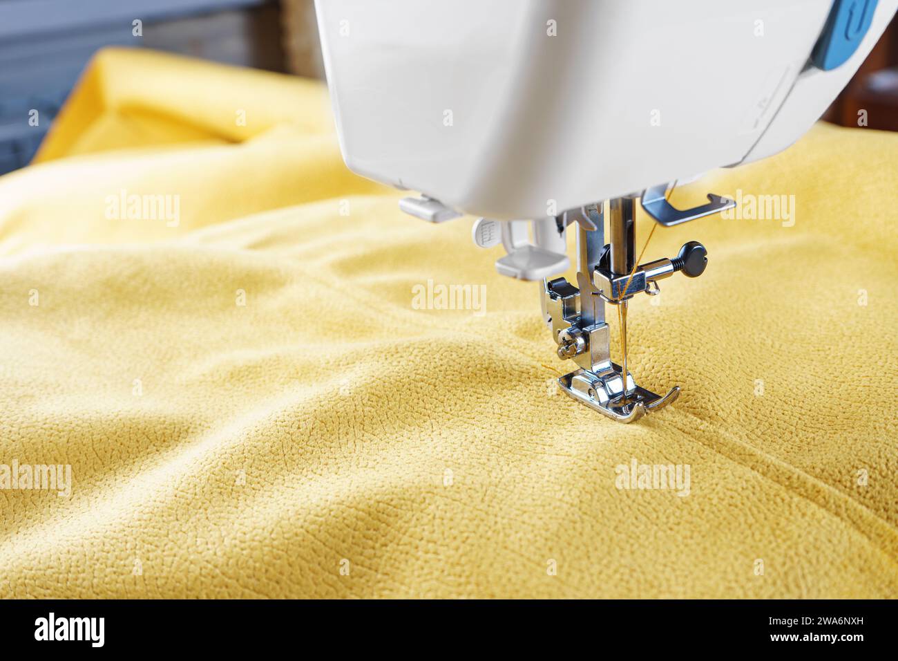 Modern sewing machine with yellow velours fabric. Sewing process ...