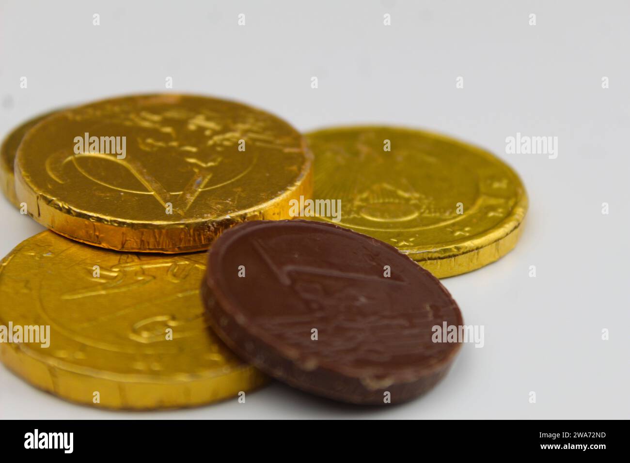 A close up photo of golden wrapped chocolate coins on a white desk ...