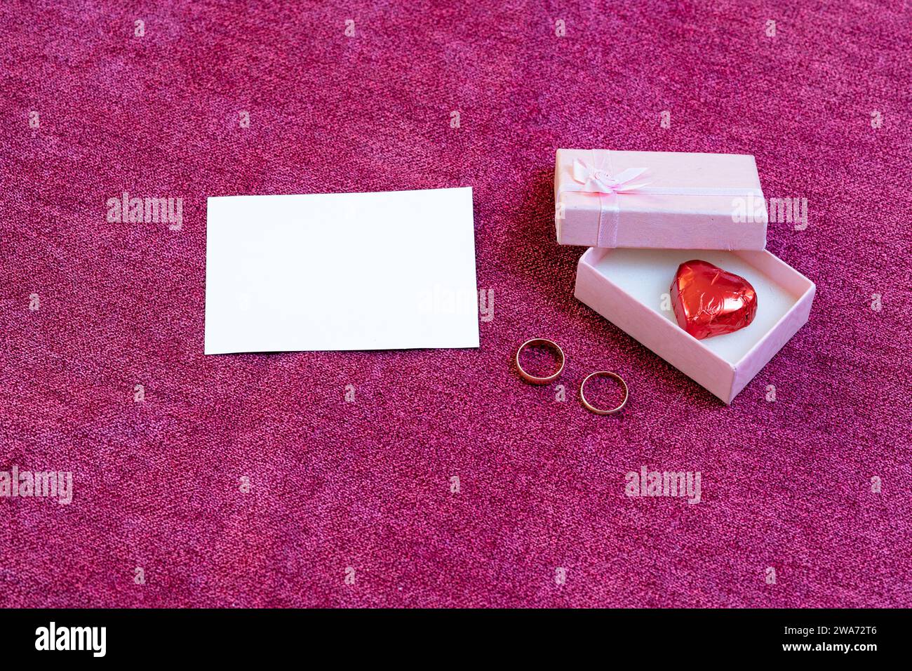 open gift box with a heart-shaped chocolate inside and engagement rings ...