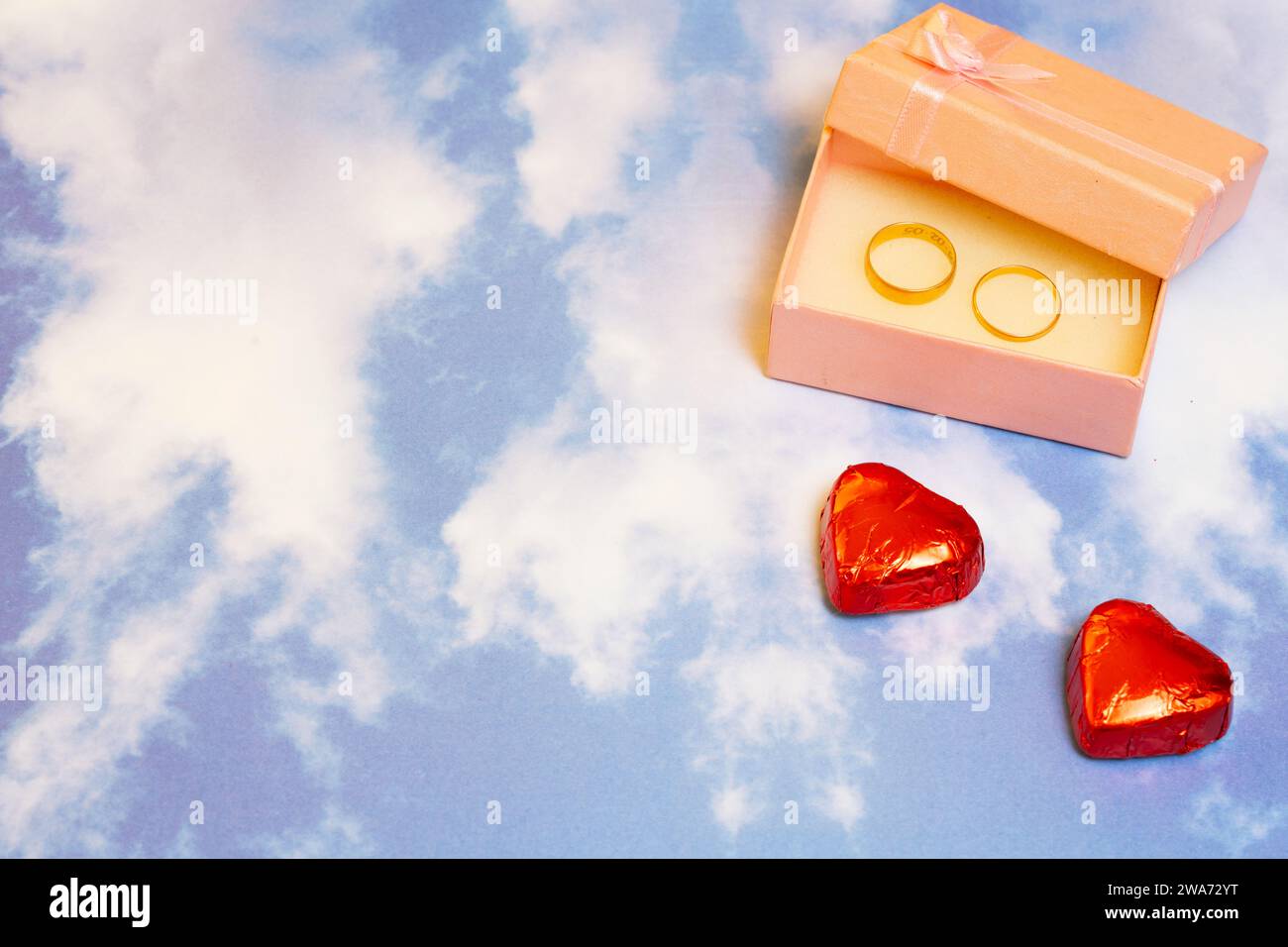 engagement rings on a gift box with two heart-shaped chocolates on a ...