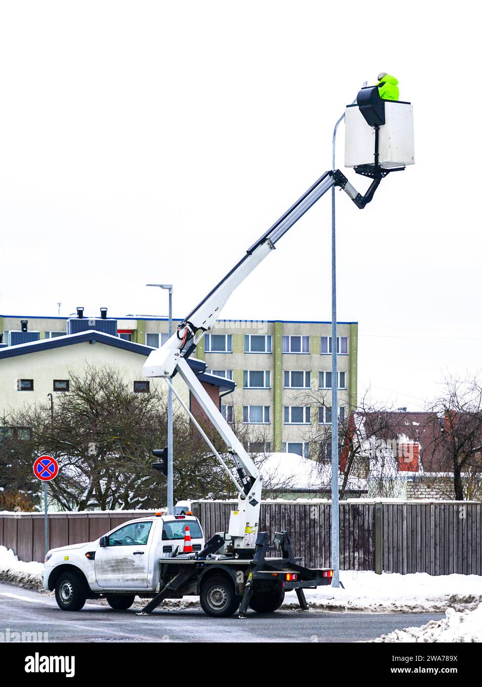 Worker installs LED street lighting using a lifting platform mounted on ...