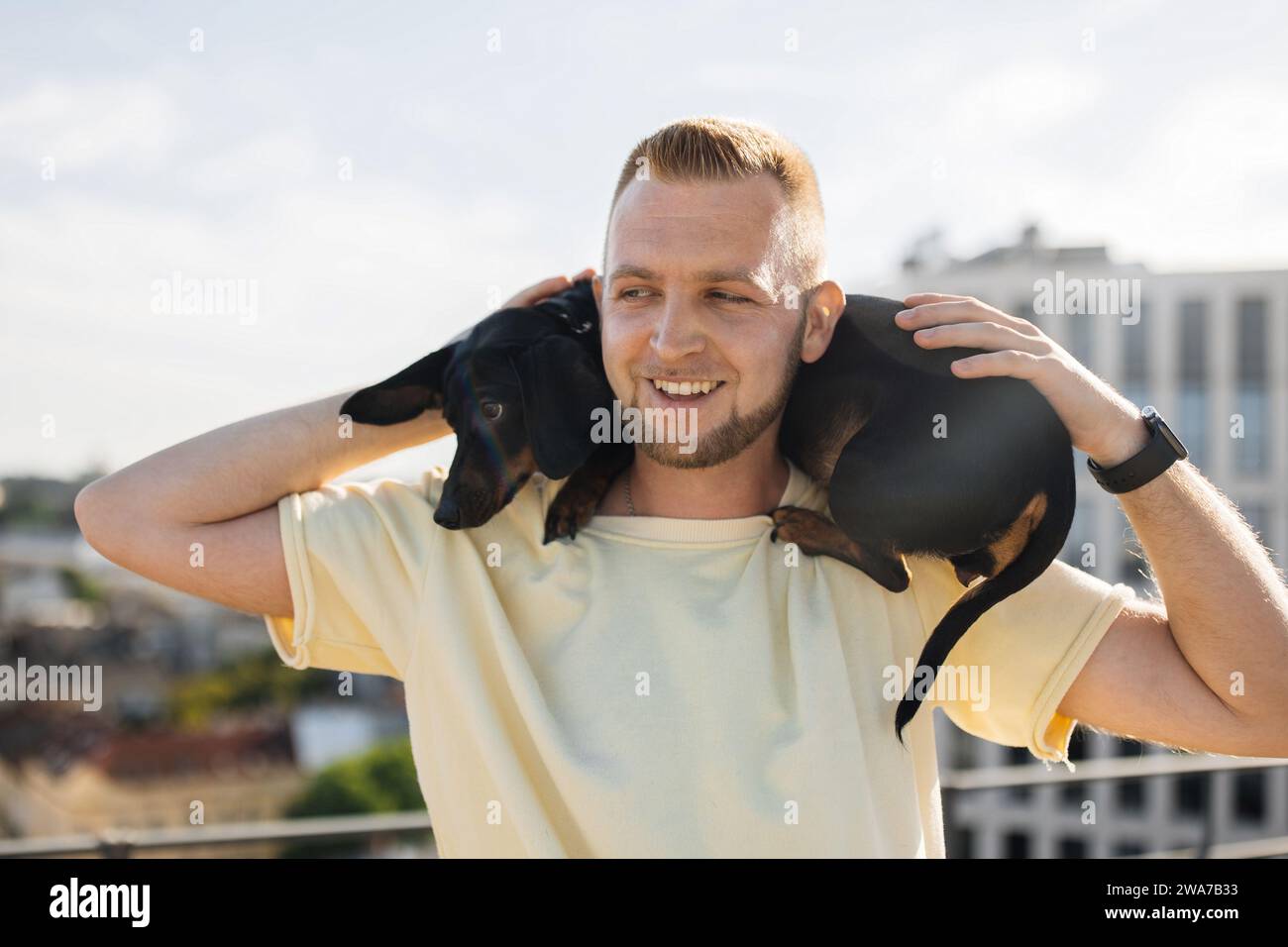 Cheerful owner holding small black dog over his neck outside Stock ...