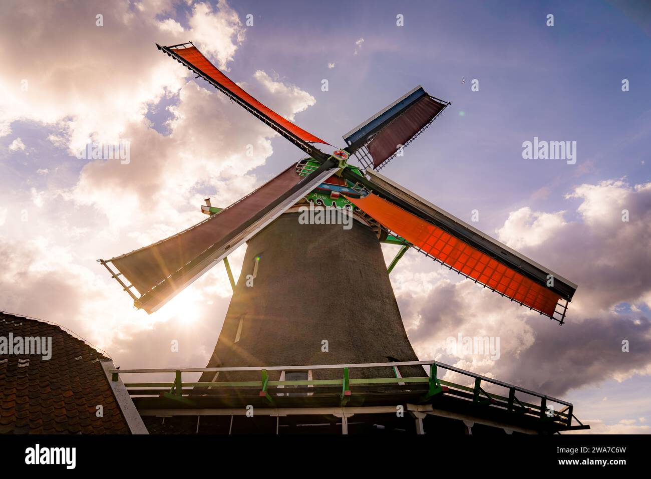 sun shining throug historical dutch windmill during colorful sunset ...