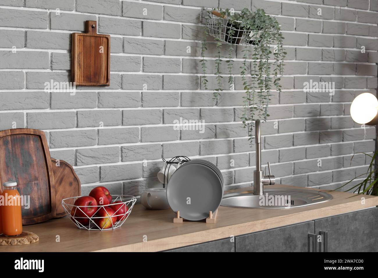 Wooden countertop with sink, apples and plate rack in modern kitchen ...
