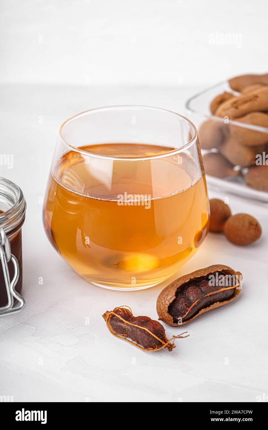 Glass of tasty tamarind drink and fruits on white background Stock ...