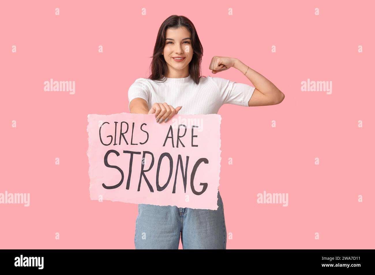 Young woman with sign GIRLS ARE STRONG on pink background. Feminism ...