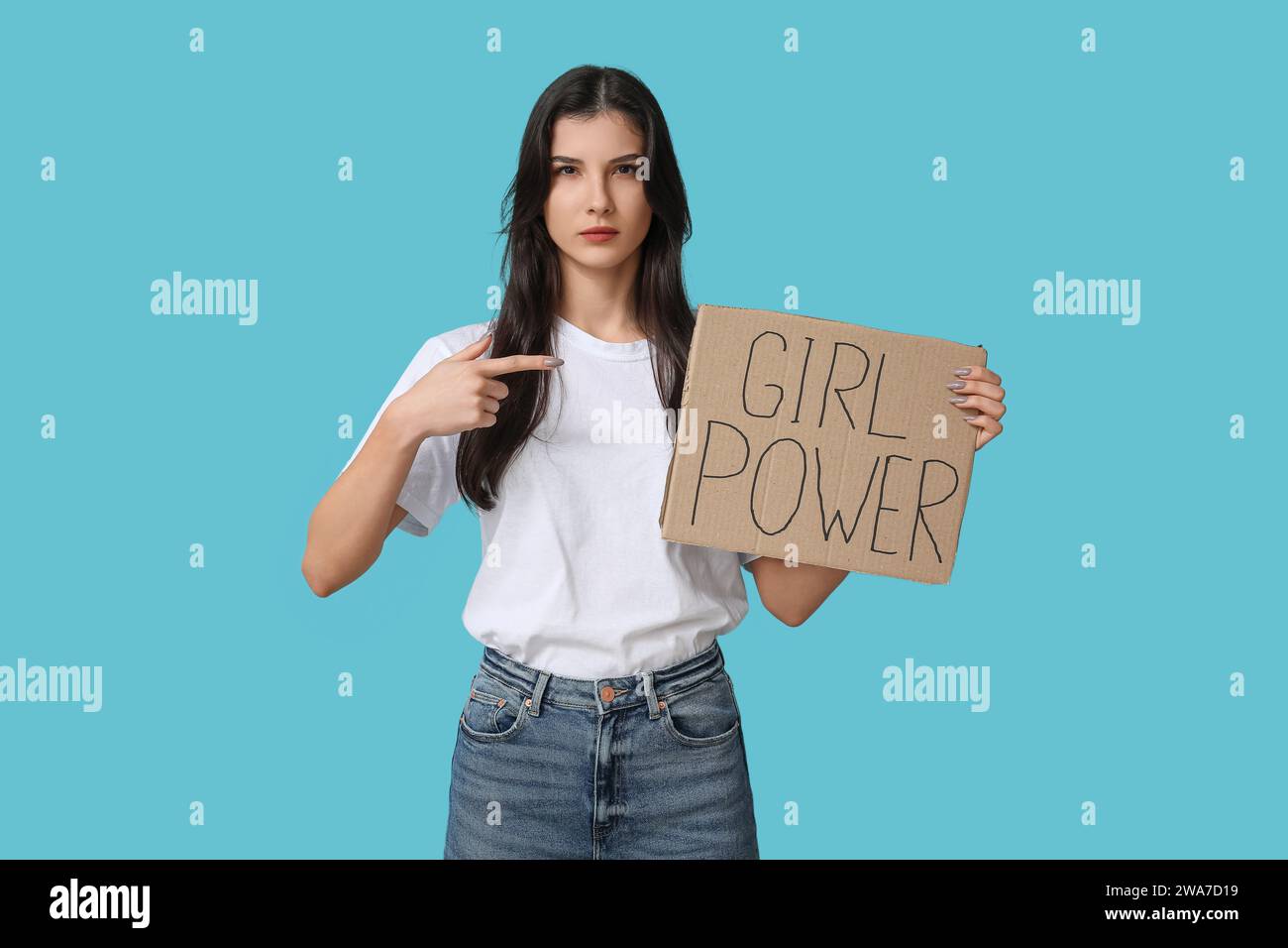 Young woman pointing at cardboard with text GIRL POWER on blue ...