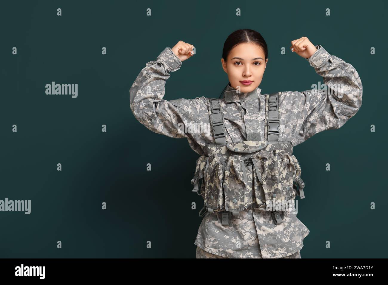 Young female soldier flexing muscles on green background. Feminism ...