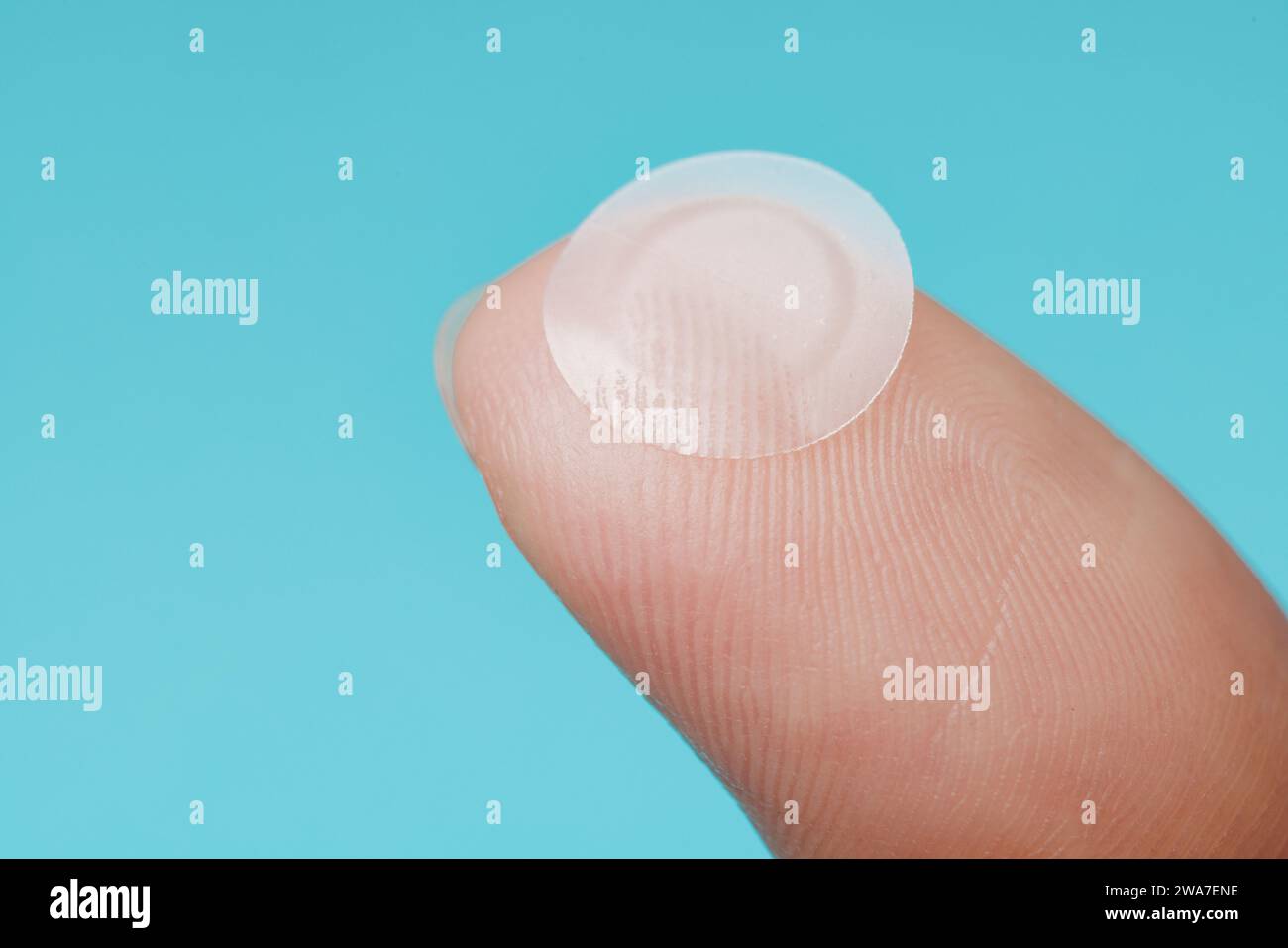 Close-up round acne patch on finger on blue background. Acne patches ...