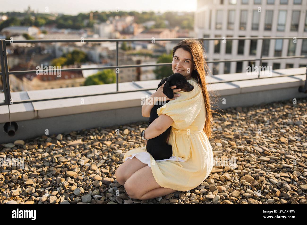 Attractive lady sitting on ground and hugging dog on roof Stock Photo ...