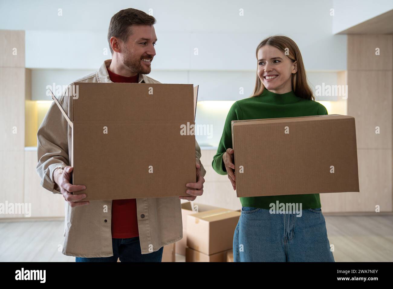 Happy loving couple spouses moving in new apartment carrying cardboard ...