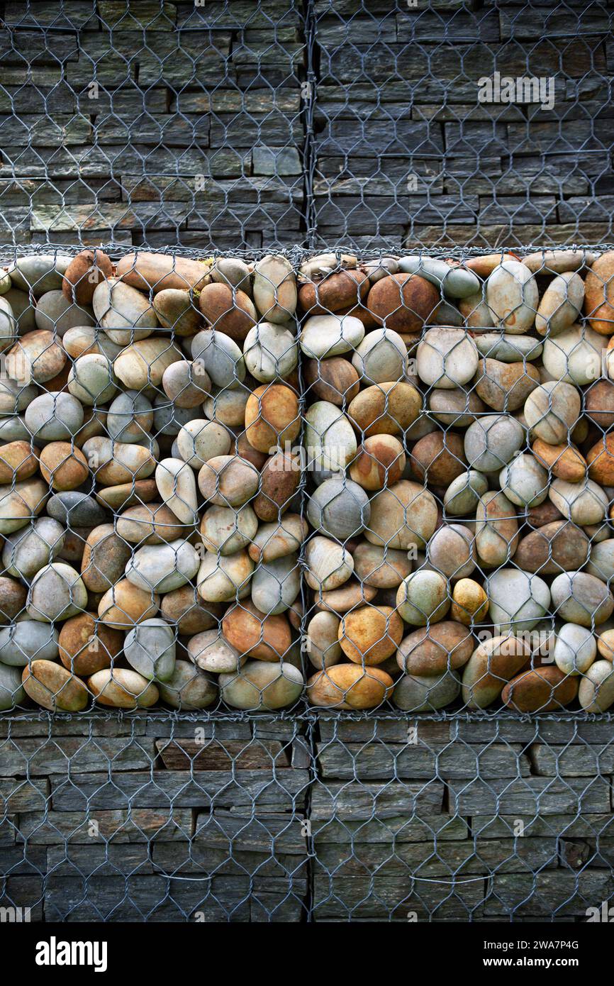 Pebbles embedded in a flat stone wall Stock Photo - Alamy