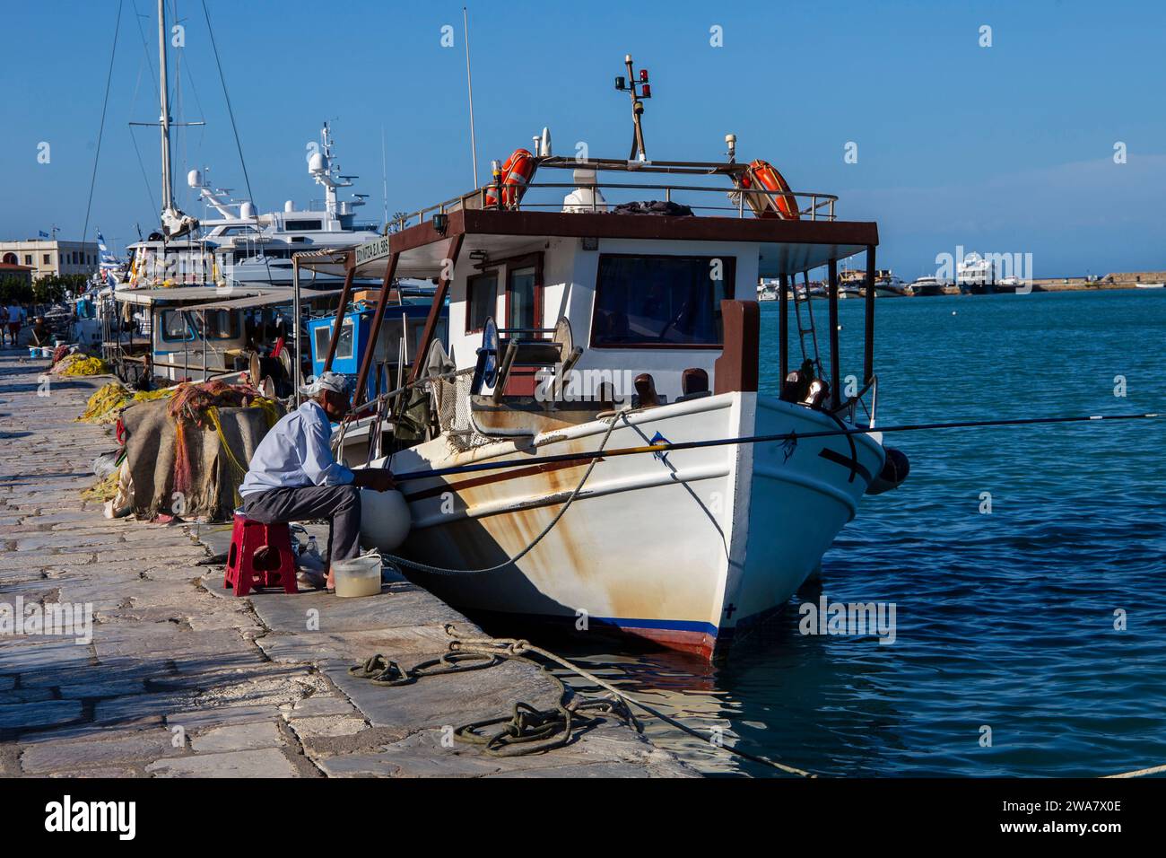 Fisherman sat on the harbour wall Zakynthos (Zante) town Greece by a ...