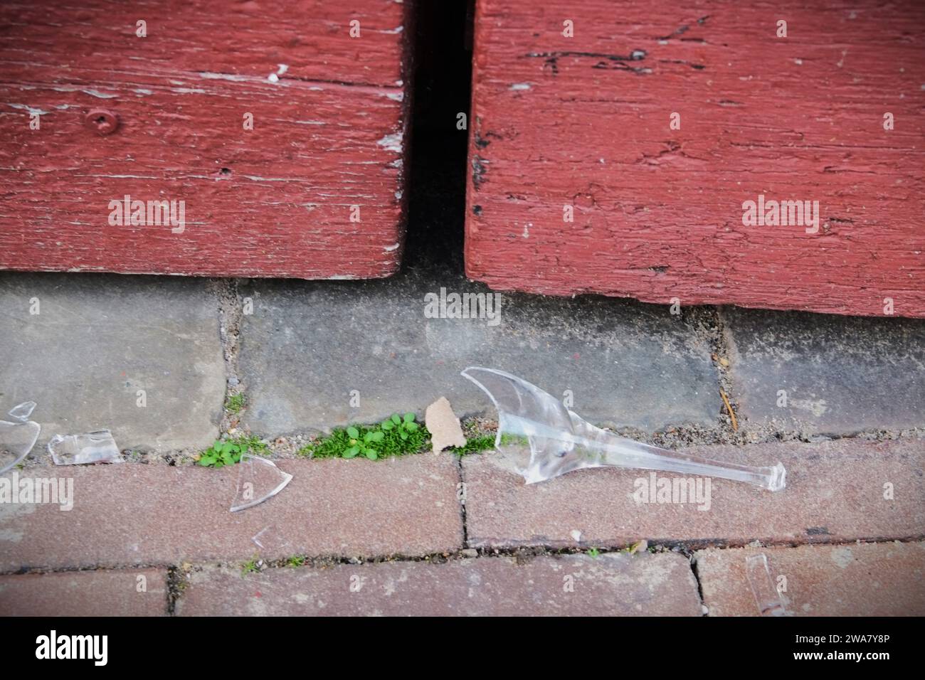 Champagne flute glass smashed to a bricked pavement in front of a crack ...
