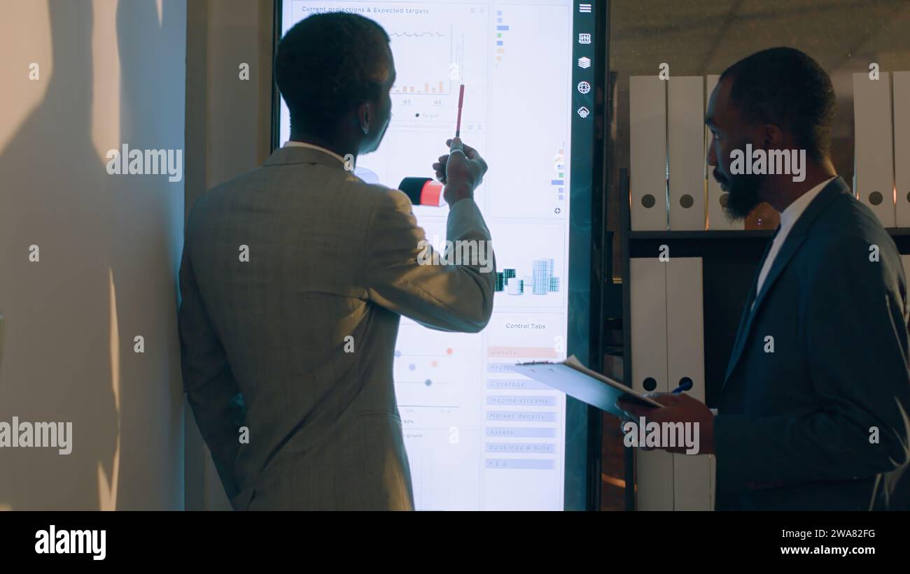 Supervisor showing employee useful datasets on digital screen to help ...