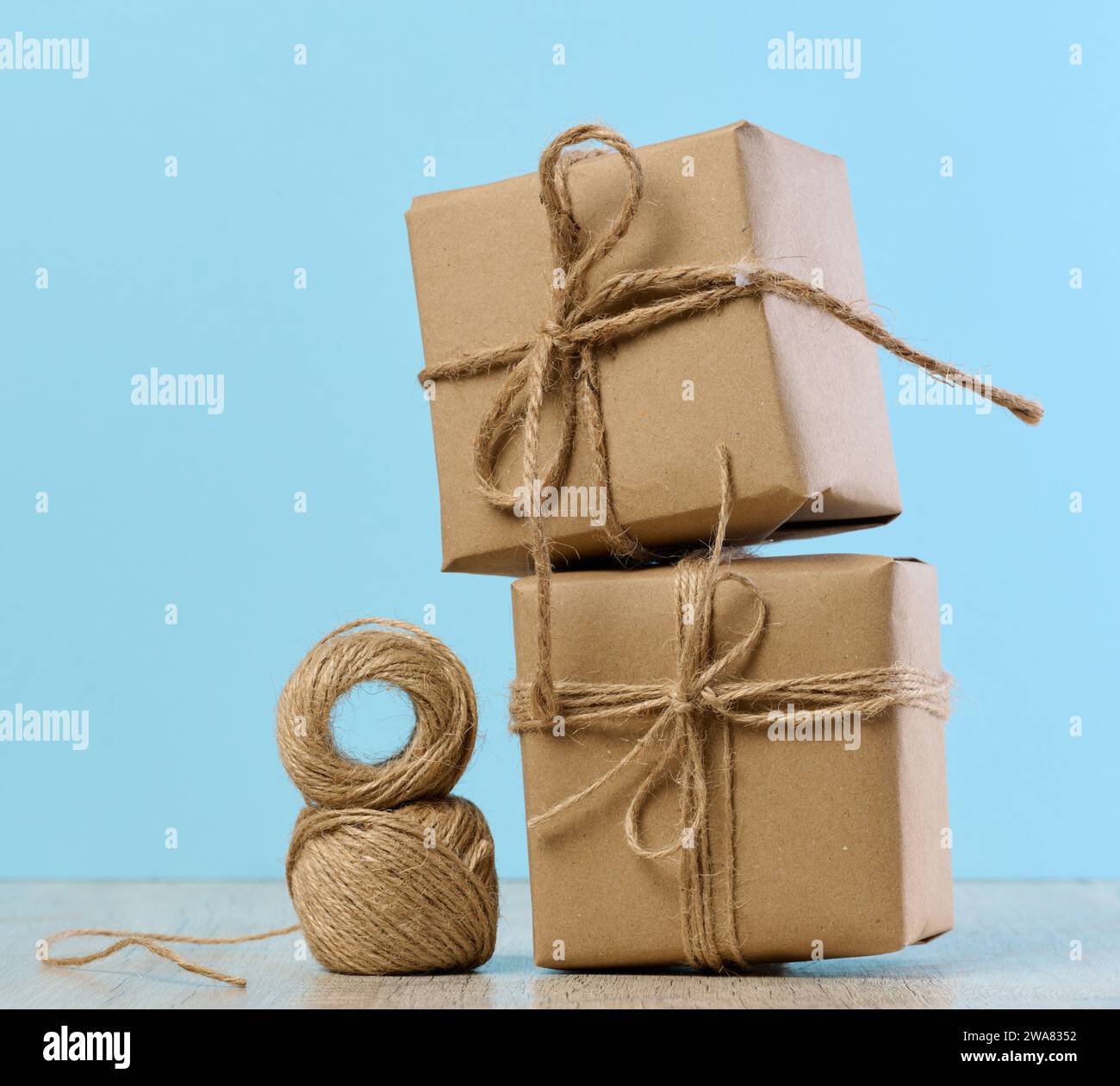 The box is packed in brown craft paper and tied with a rope on a blue ...