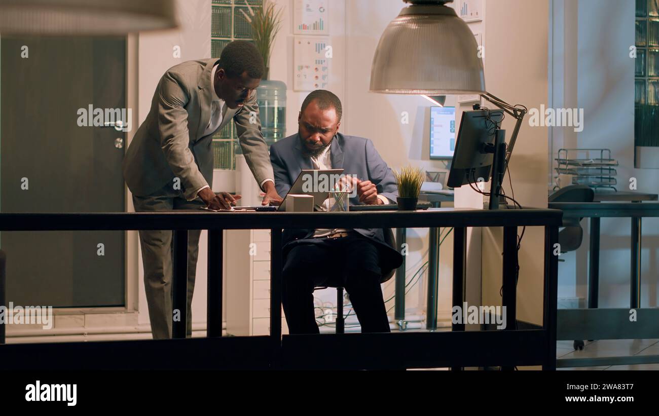 Experienced employee bringing laptop to help coworker solve unfinished ...