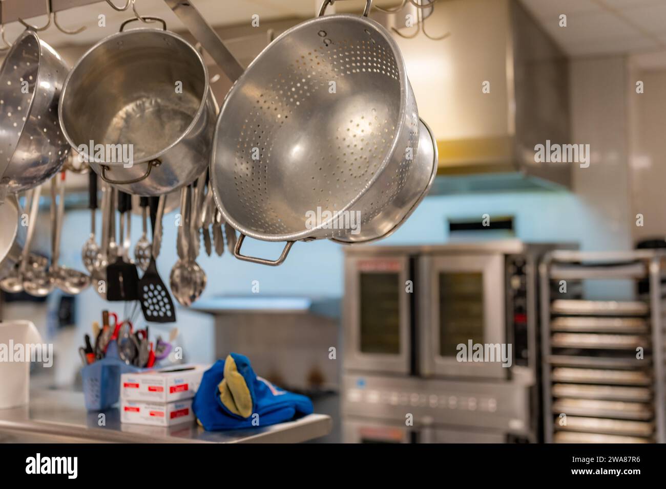 Stainless steel pots and pans and other cooking utensils hanging in a ...
