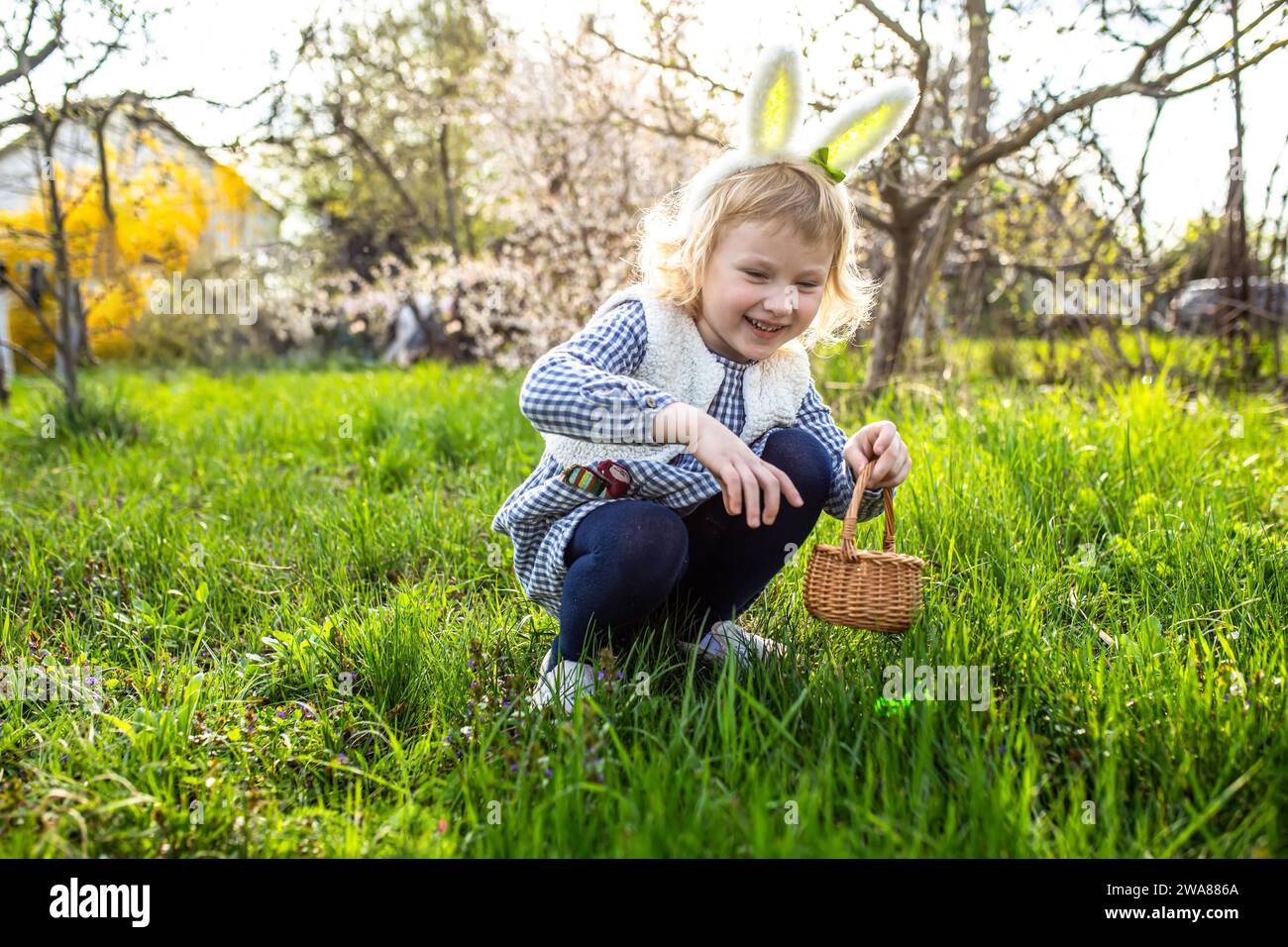 little girl collecting Easter eggs outdoors during an Easter Egg hunt ...